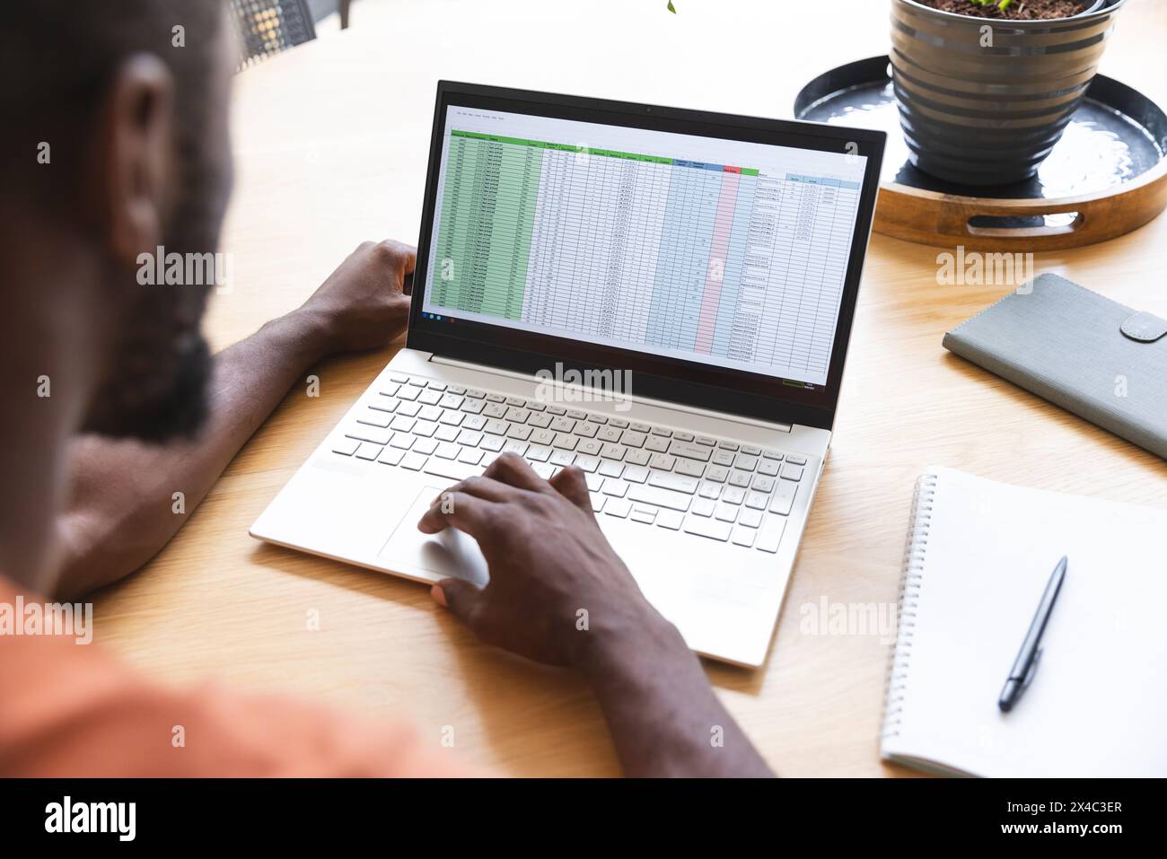 An African American male studying spreadsheet on laptop at home ...