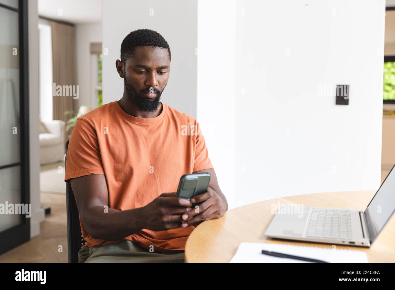 At home, African American male homeowner holding smartphone, wearing ...