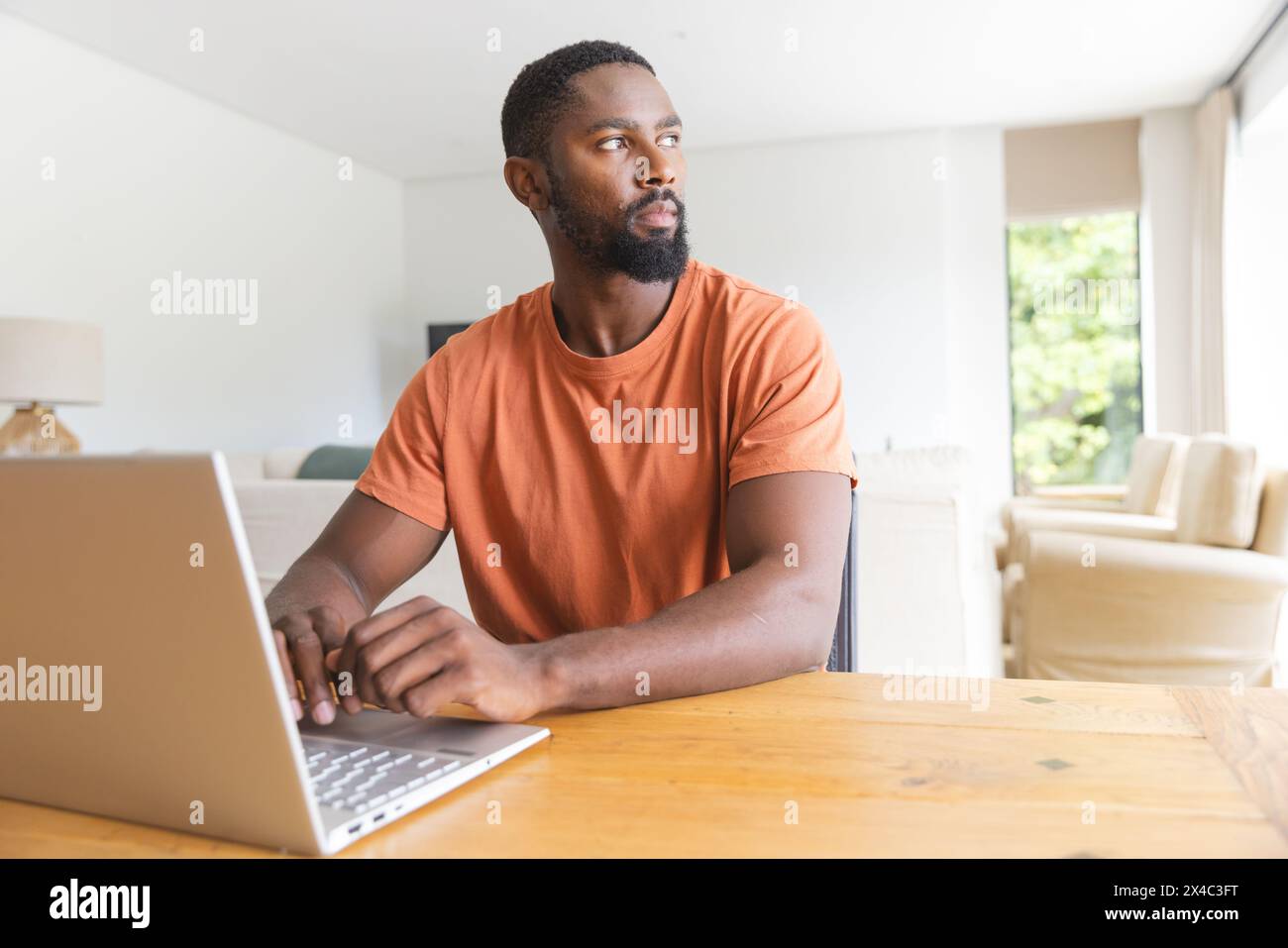 At home, African American male homeowner using laptop at a table ...