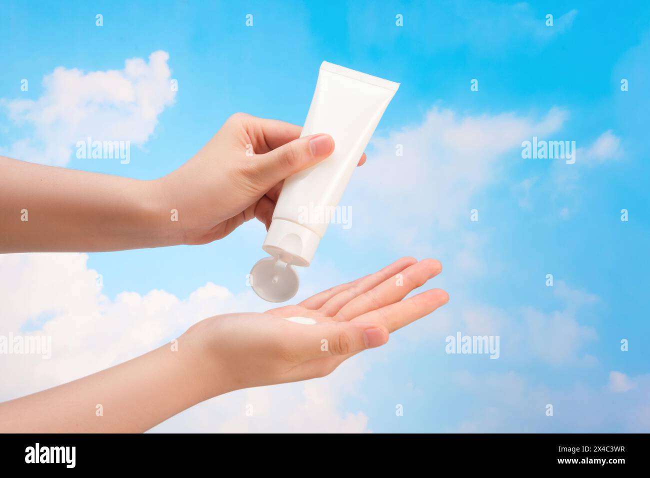 Against the blue sky with white cloudy, hands of woman are applying ...