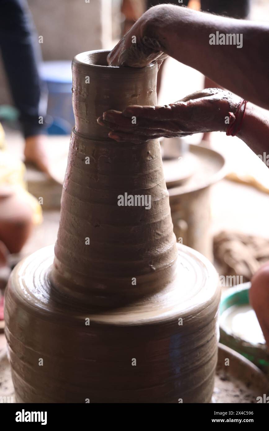 The potter works on a pottery wheel to made of soft colored clay, retro ...
