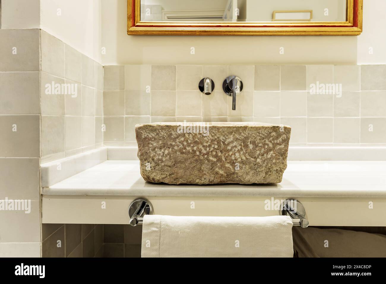 Bathroom with long white marble countertop, raw stone sink and gold ...