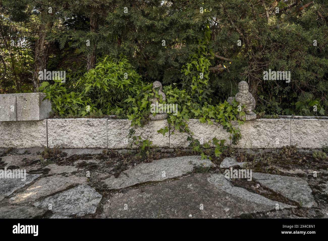 Perimeter fence of a garden with hedges and decorative stone objects ...