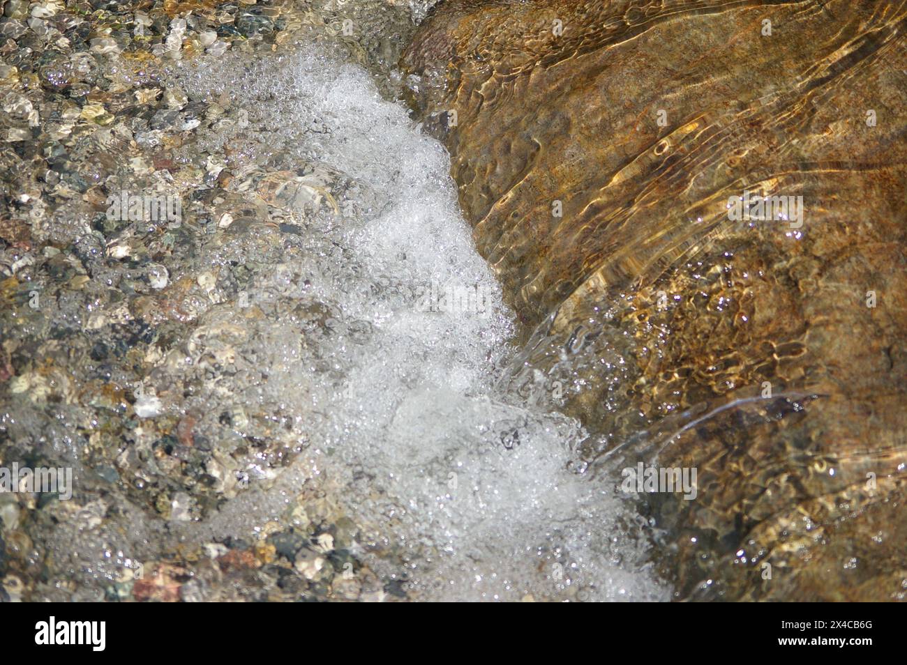 Clear water running over rocks in the sunlight Stock Photo - Alamy