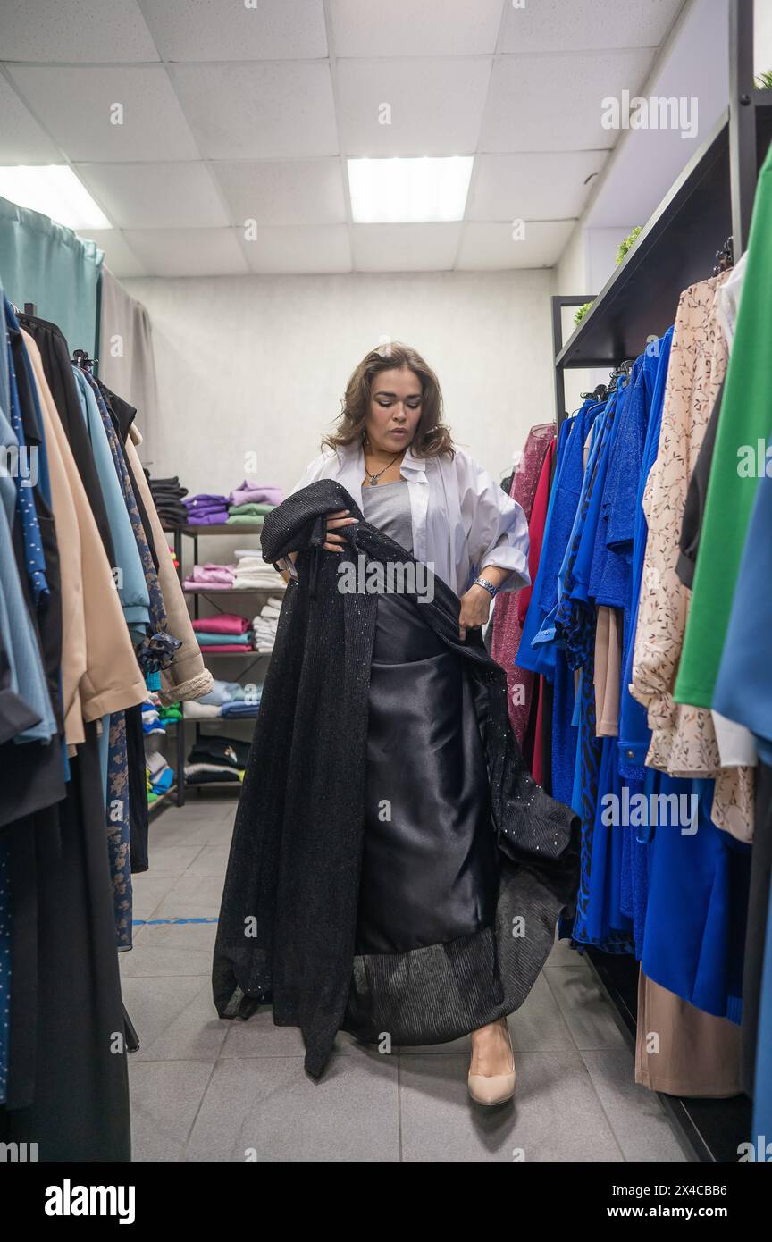 A fat woman chooses clothes in a plus size store. Vertical photo Stock ...