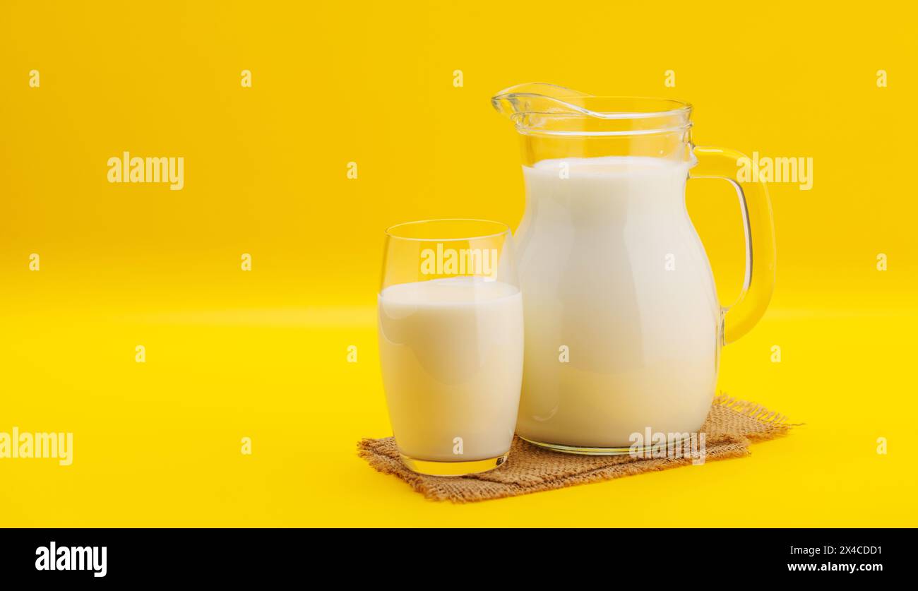 Fresh Milk in Pitcher and Glass on yellow background with copy space ...