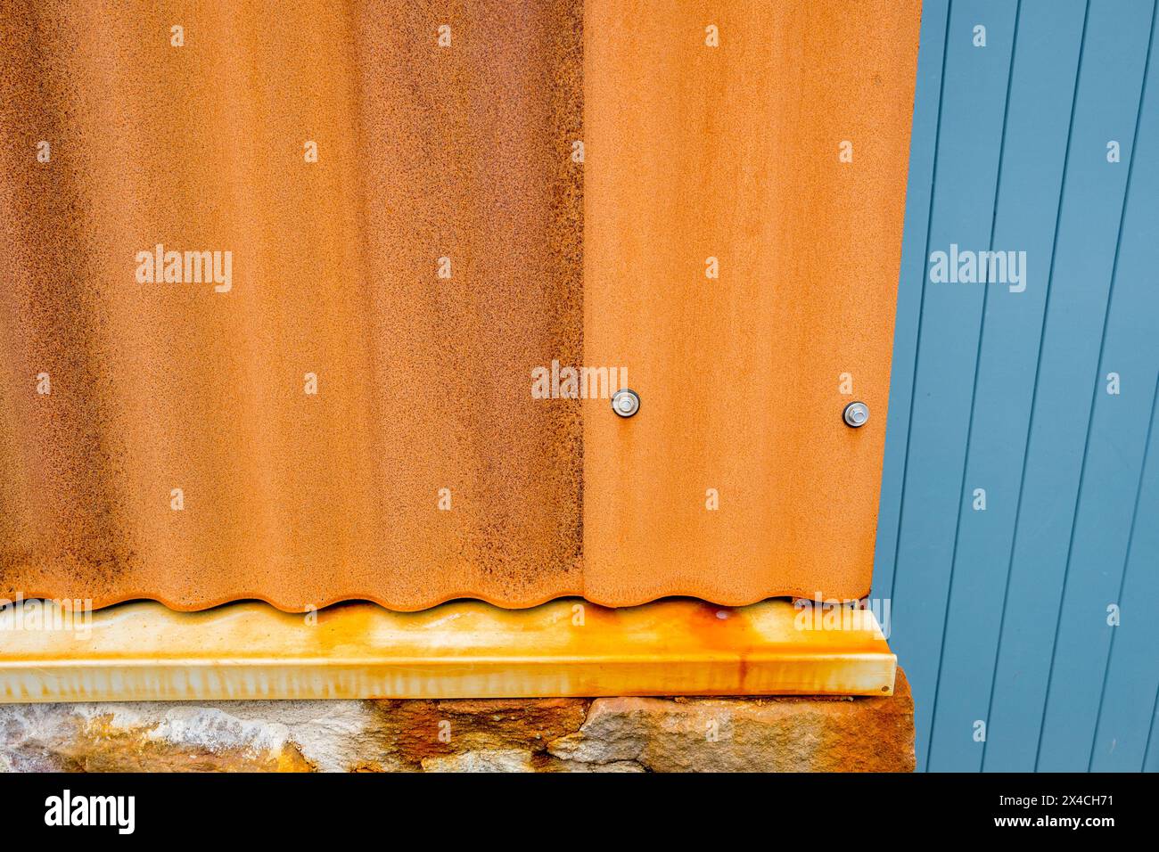 Thin layer of rust on a corrugated steel sheet and local stone wall and ...