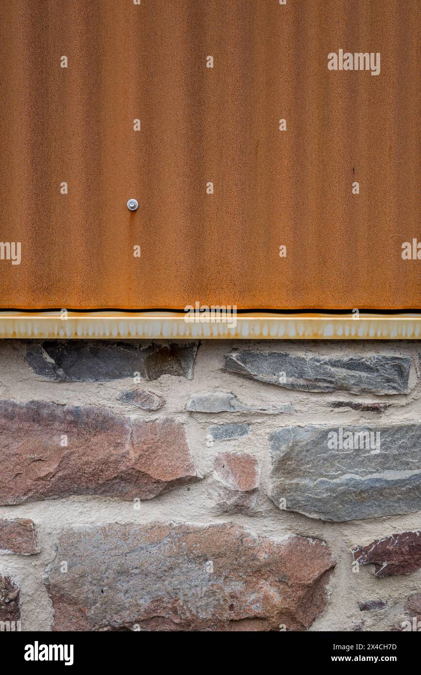 Thin layer of rust on a corrugated steel sheet and local stone wall ...