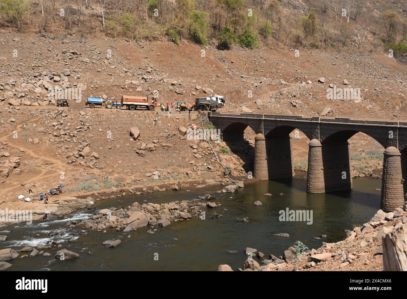 Water tanker trucks are seen filling water from Vaitarna river near ...