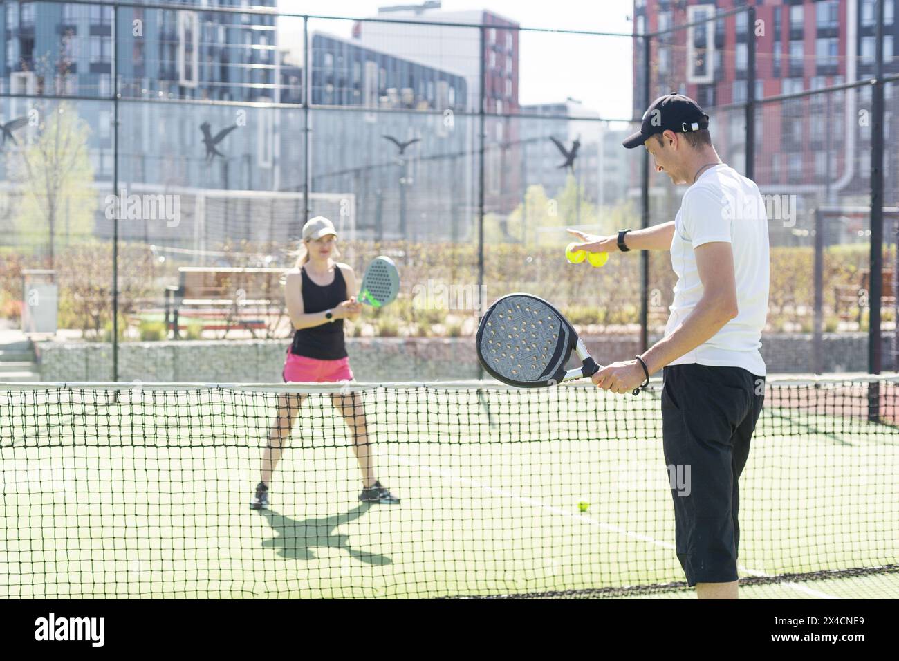 Portrait of positive young woman and adult man standing on padel tennis ...