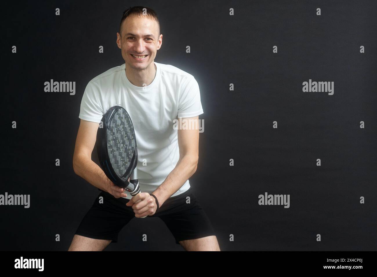 Portrait of man playing paddle tennis in position to hit a backhand ...