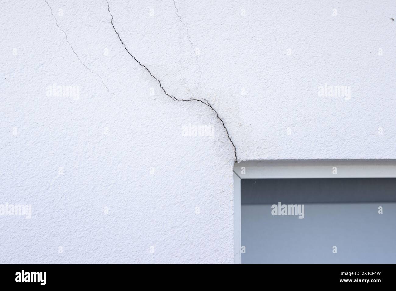 Detail of a crack in the facade cladding near the window lintel area ...