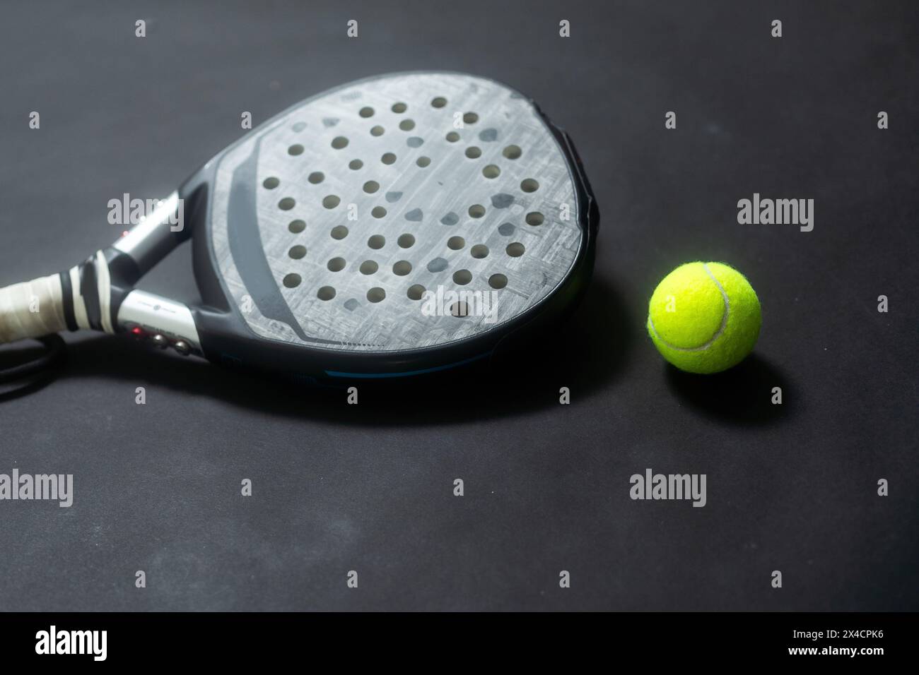 Detailed background of black and white padel racket and ball on black ...