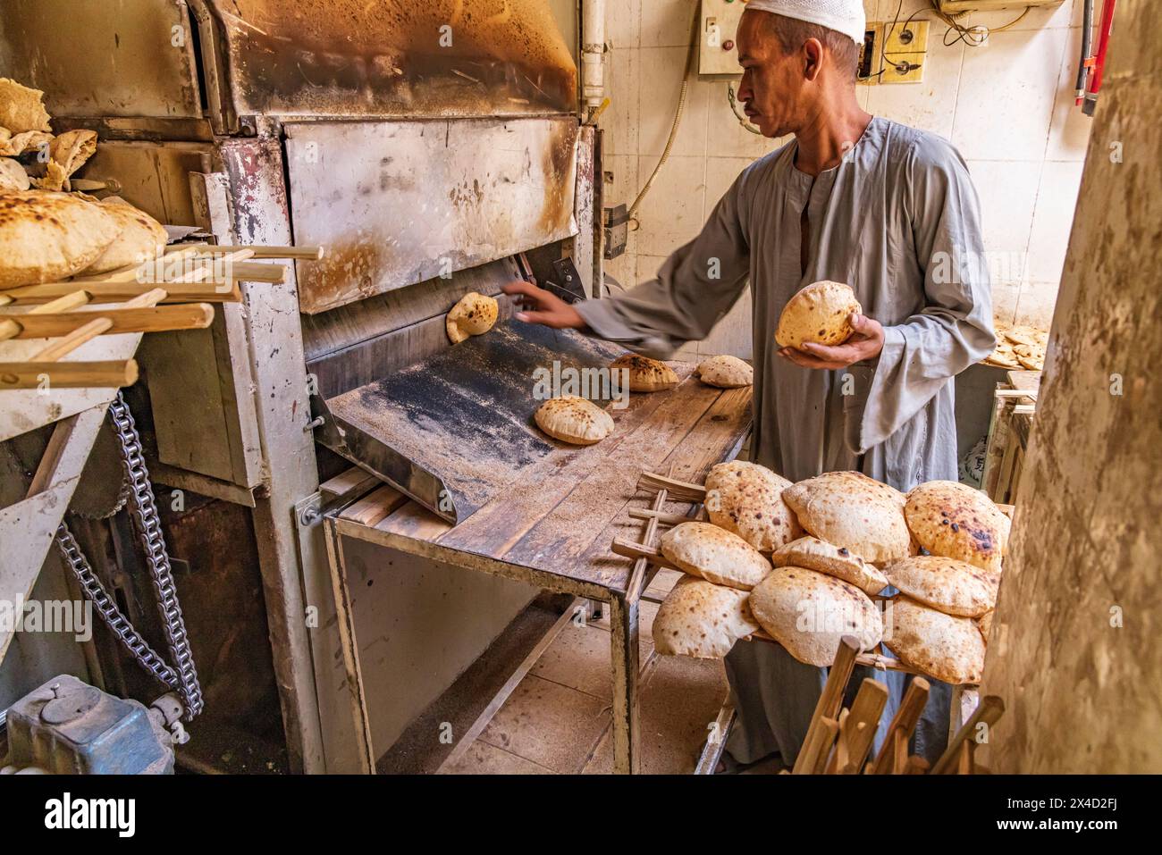 Thebes, Luxor, Egypt. Baker making pita bread with an automated oven ...