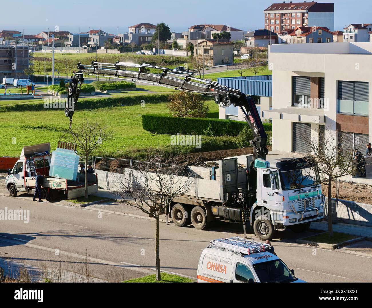 Flatbed truck delivering glass panels using a lorry mounted crane to a ...
