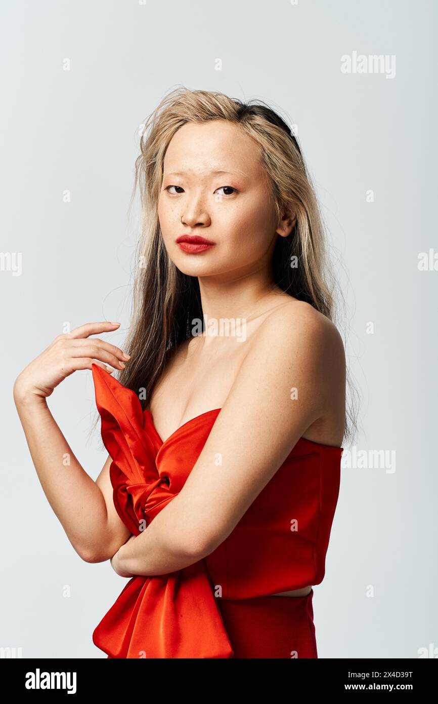 An attractive Asian woman in a vibrant red dress striking a pose for a ...