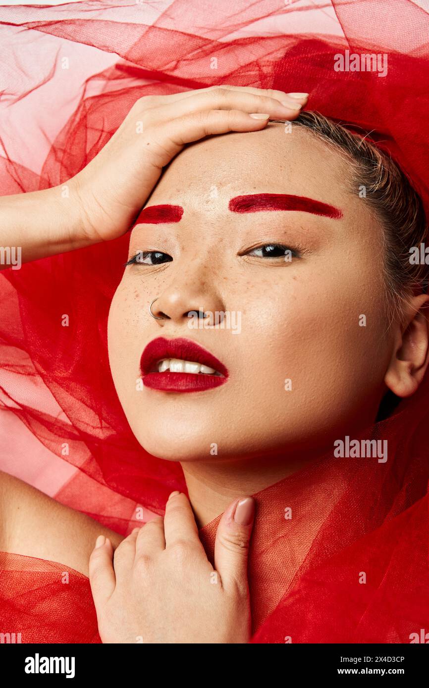 An Asian woman adorned in red makeup and a red veil poses dynamically Stock Photo - Alamy