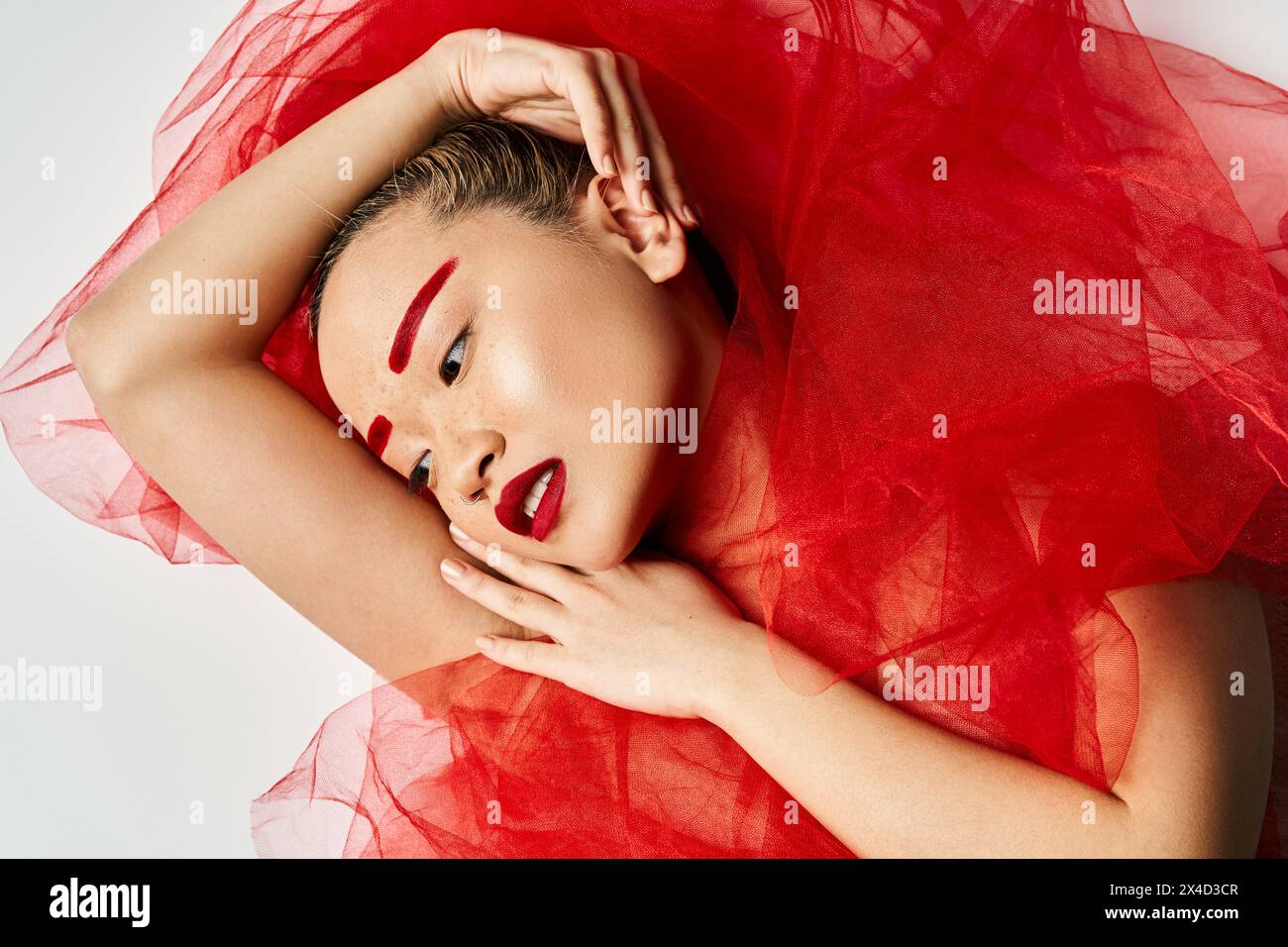 Asian woman in red dress with hands on head, striking a dramatic pose ...