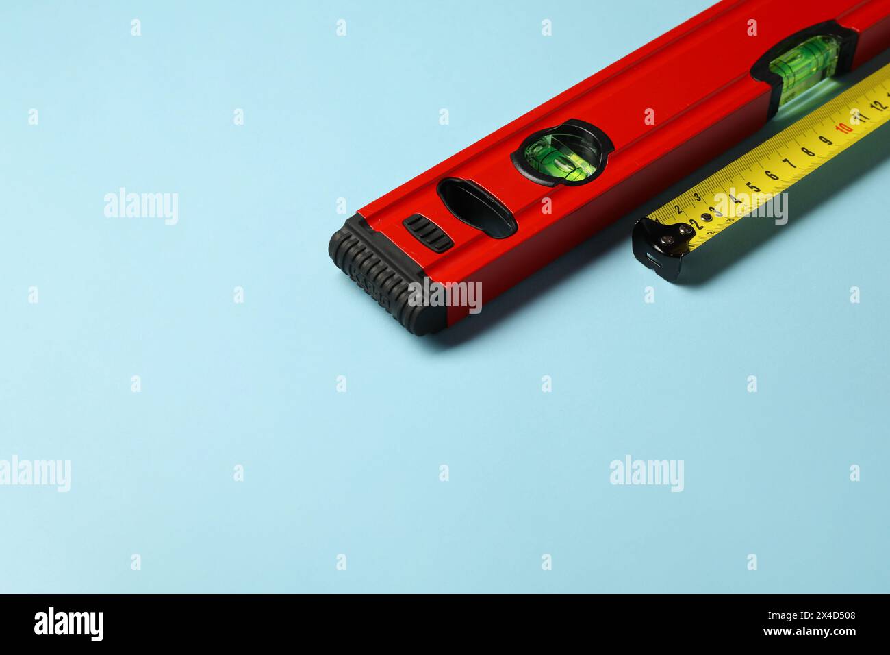Building level and tape measure on light blue background. Space for ...
