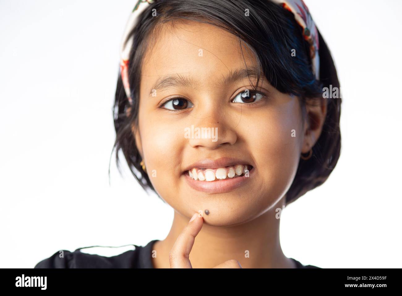 A pretty Indian girl child showing her mile on chin with smiling face ...