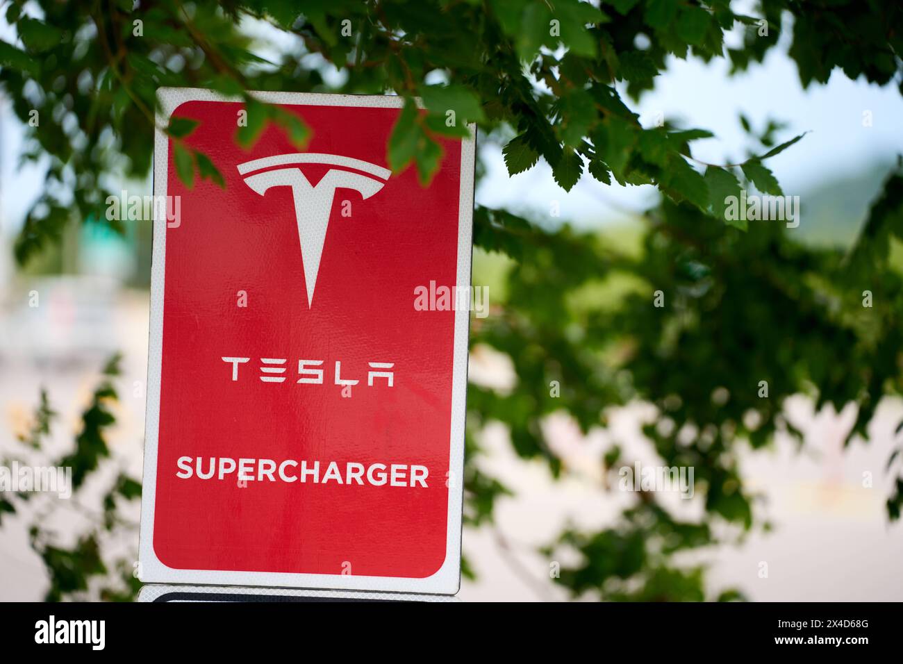 Italy - May 1, 2024: Tesla Supercharger, red sign in front of green ...
