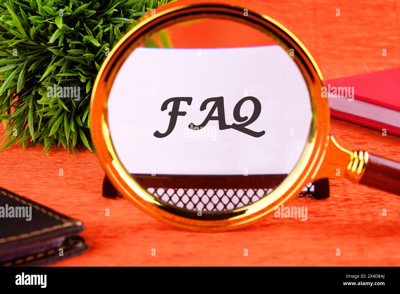 FAQ ( frequently asked questions ) text through a magnifying glass on a white business card ...