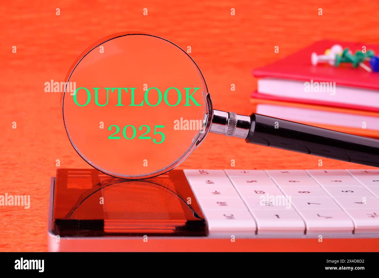 OUTLOOK 2025 through a magnifying glass on a calculator on an orange ...