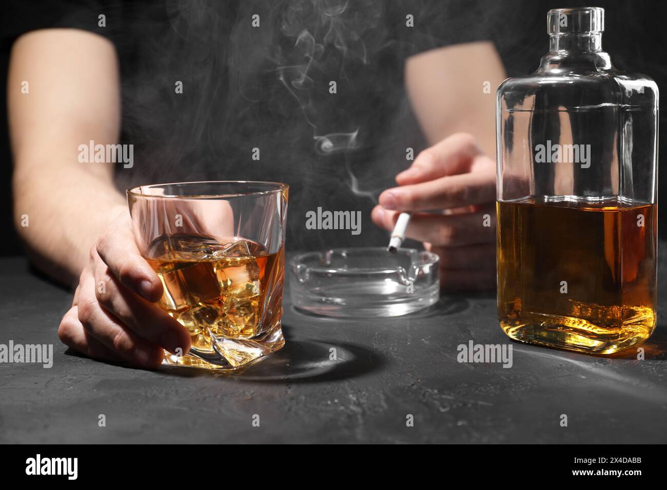 Alcohol addiction. Man with whiskey and smoldering cigarette at dark ...