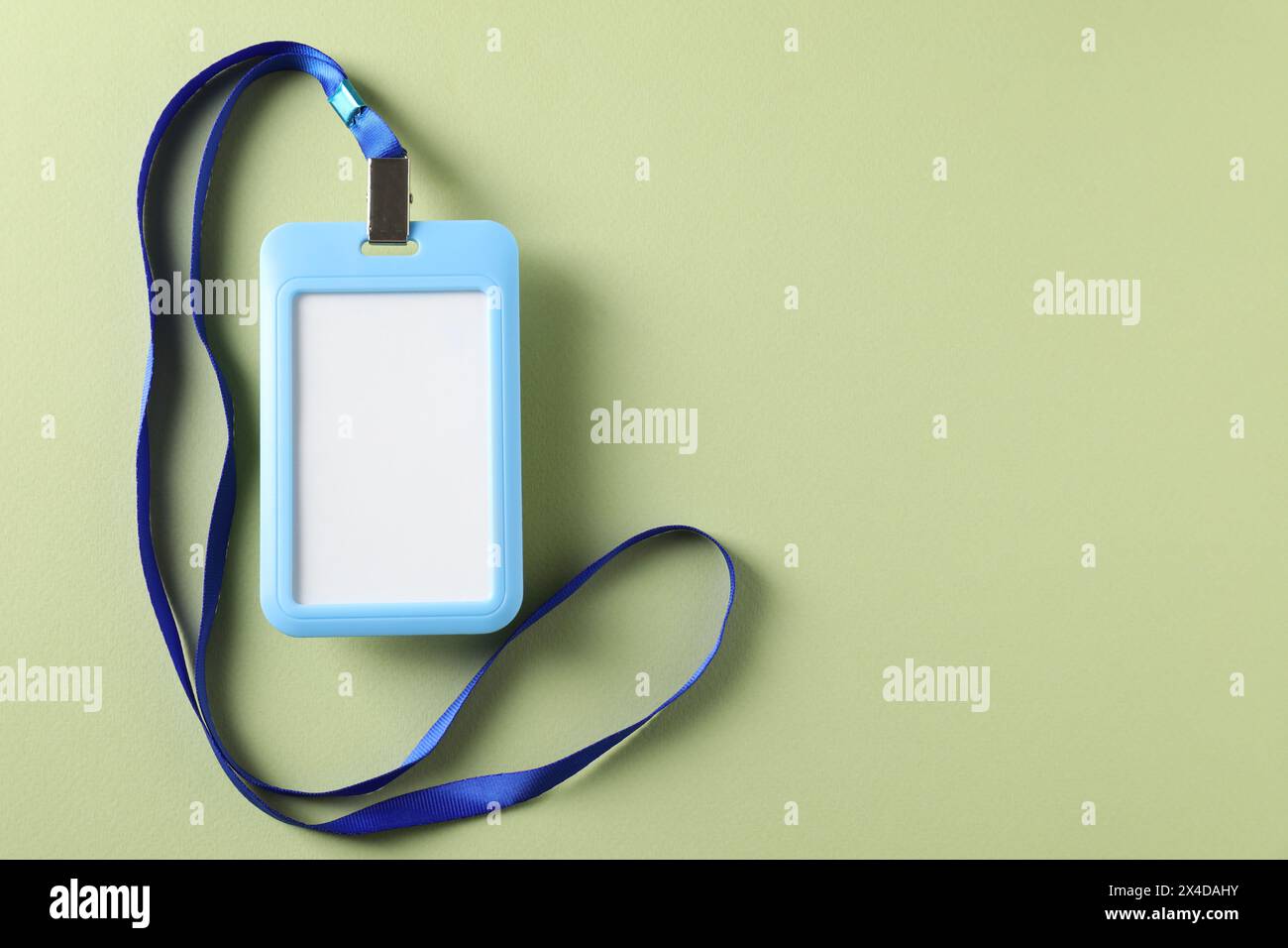 Blank light blue badge with string on green background, top view. Space ...