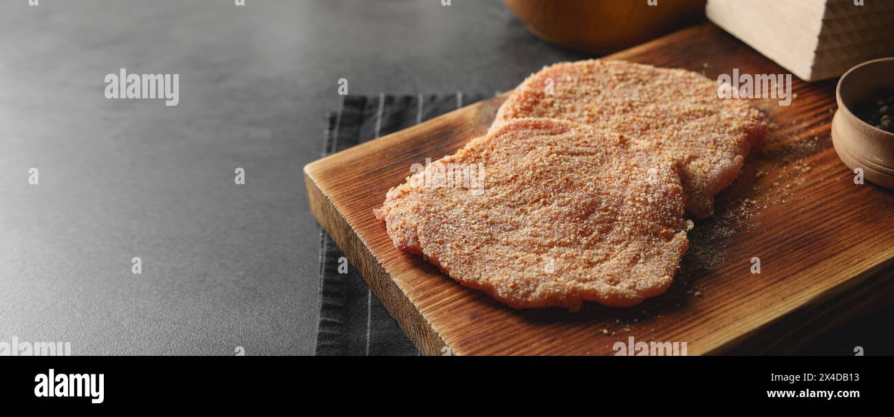Cooking schnitzel. Board with raw breaded pork slices on grey table ...