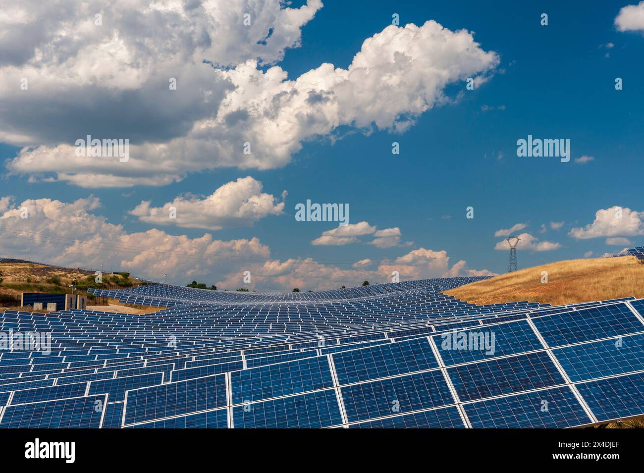 A field of solar panels at a solar power plant, under a cloud-filled ...