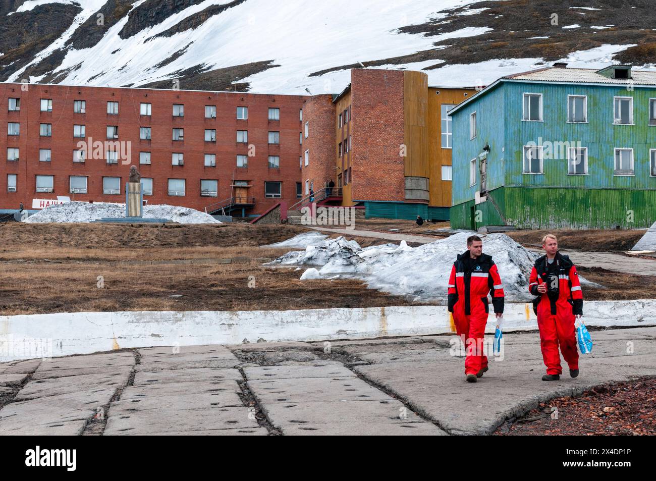 Men in arctic protective clothing walk past apartment buildings ...