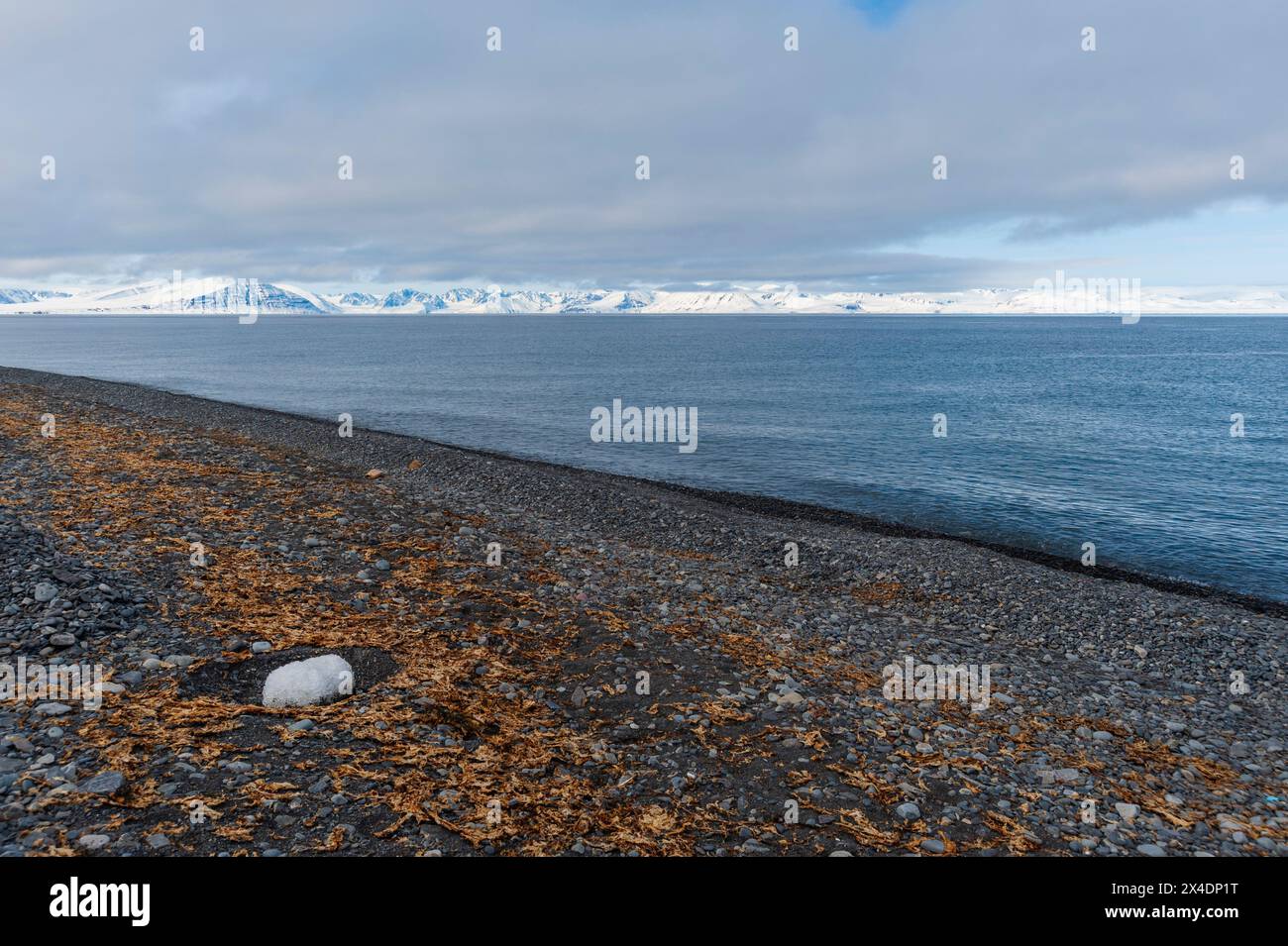 A rocky beach faces Mushamna Bay and snow covered mountains ...