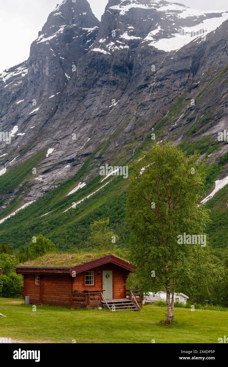 A primitive wood hut nestled in a verdant valley at the base of ice ...