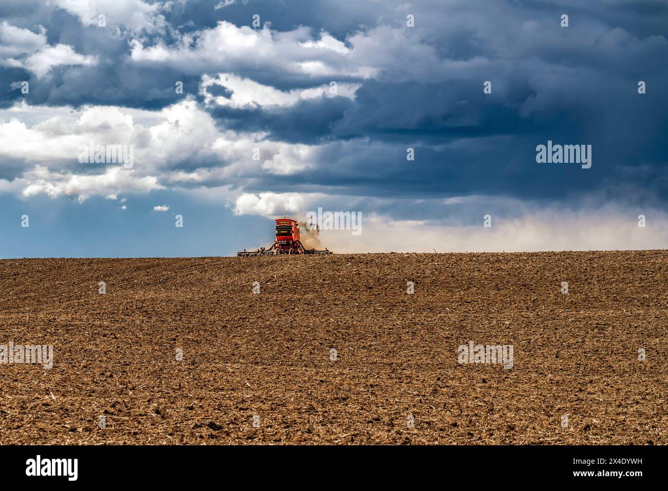 Landwirt mit Traktor bei der Feldarbeit, wirbelt Staubwolken auf ...