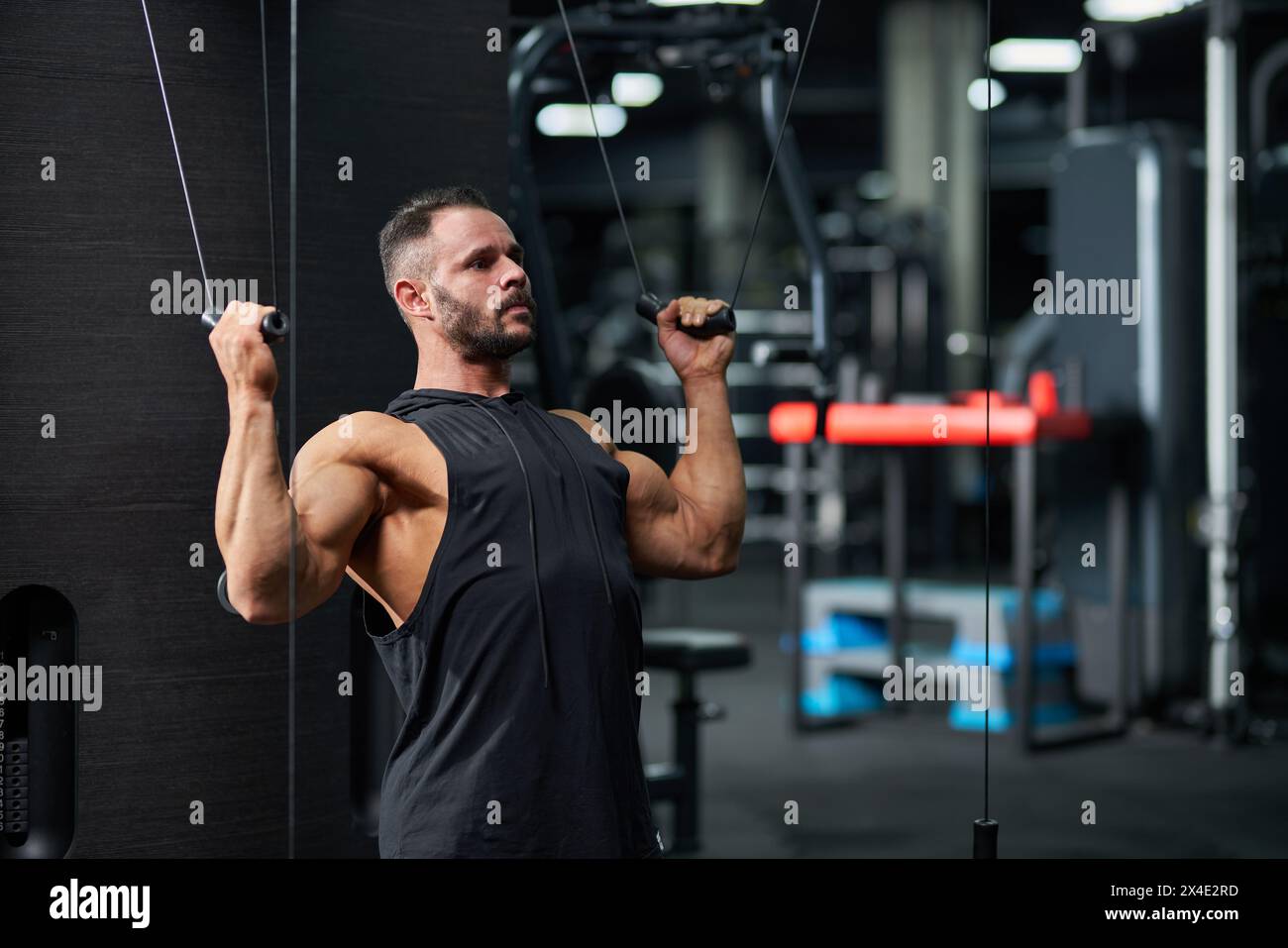 Focused sportsman wearing black tank top, exercising for strong biceps ...