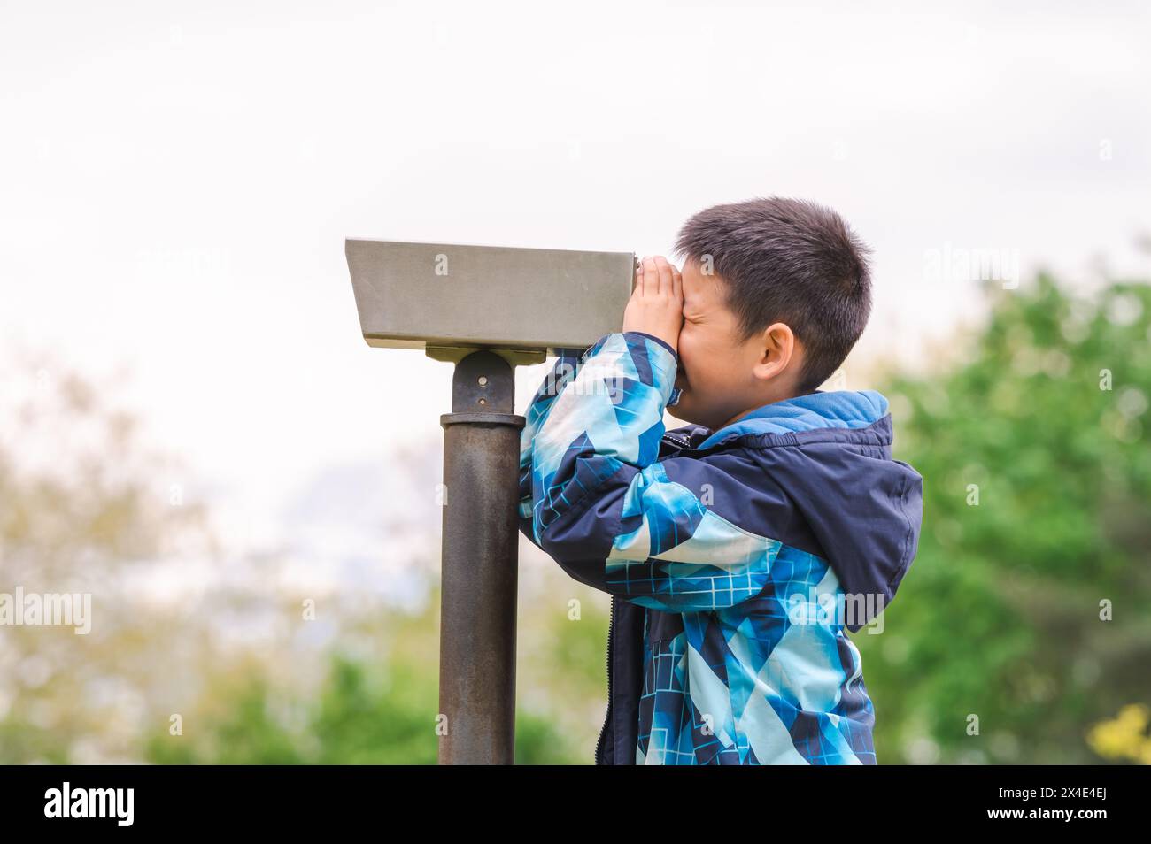 One boy looking in telescope in park. Tourists on observation deck ...