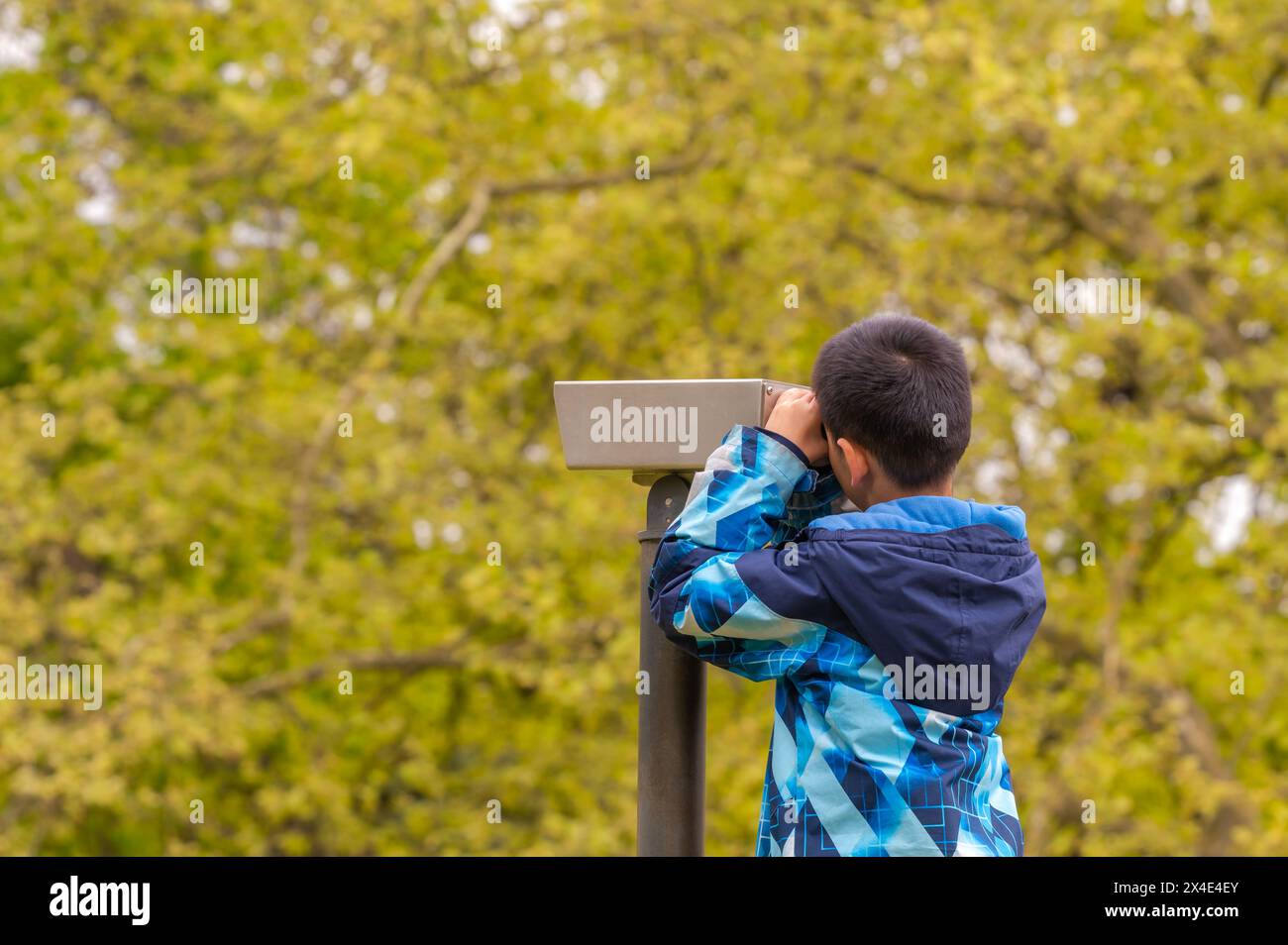 One boy looking in telescope in park. Tourists on observation deck ...