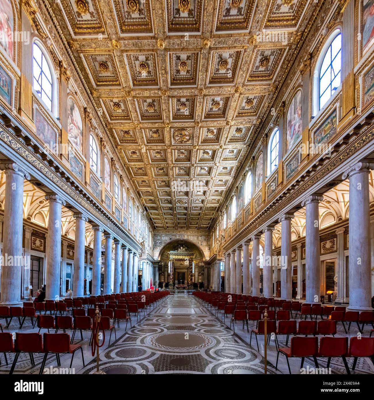 Opulent hall with gilded ceiling and marble columns, lined with rows of ...