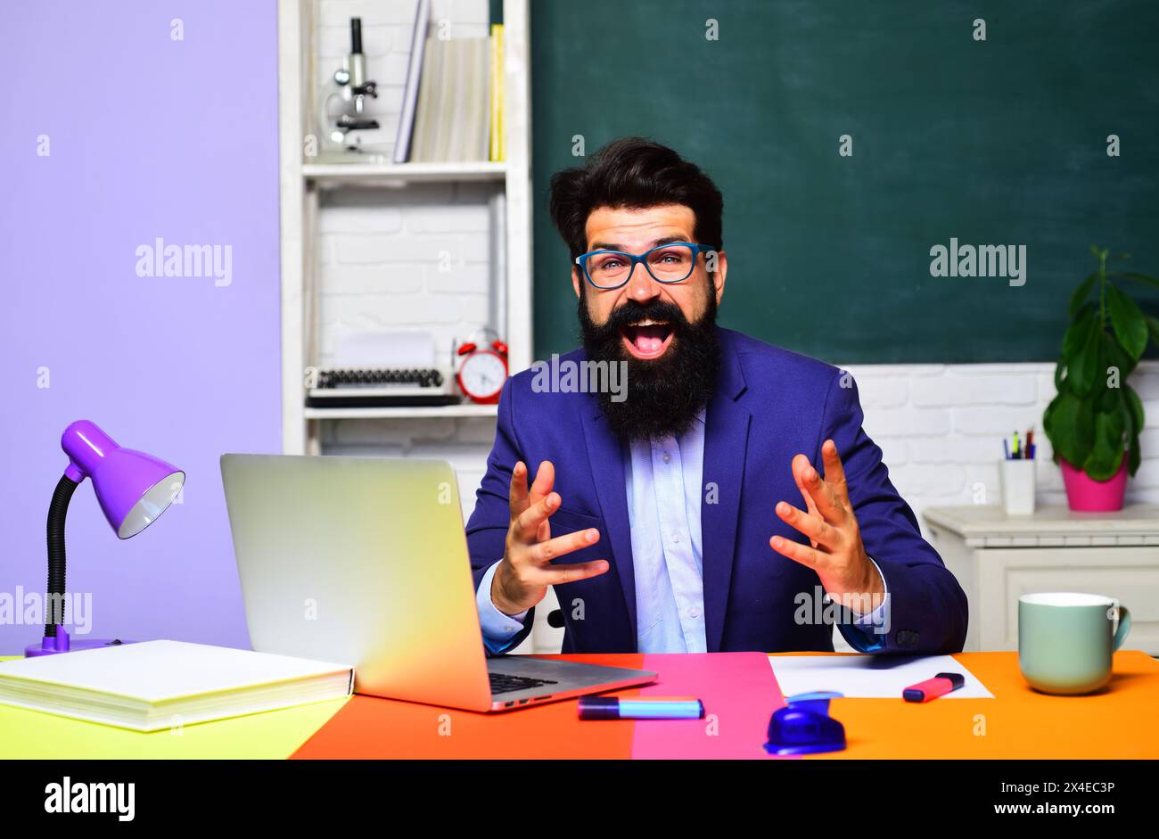 Happy male school teacher or university professor in classroom at desk ...