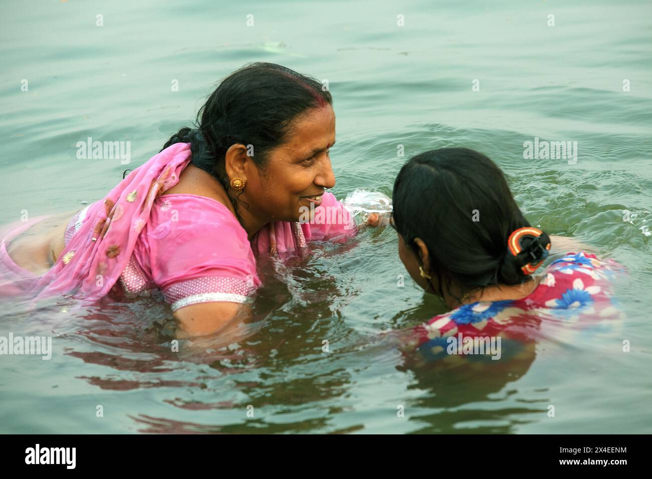 Two women pilgrims immersed in the Ganges River at Varanasi, India ...
