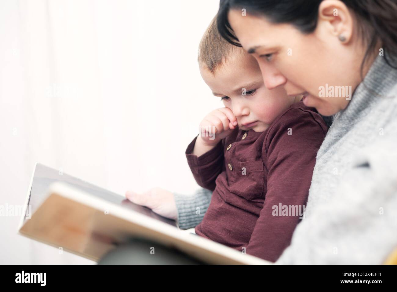 A woman and a child are reading a book together. The child is looking ...