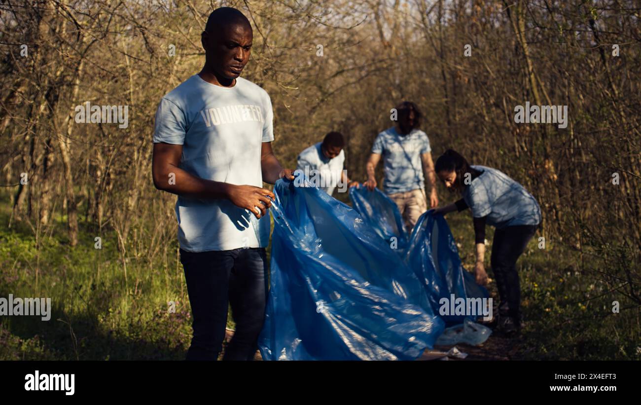 Diverse volunteers collecting garbage and junk from the forest area ...