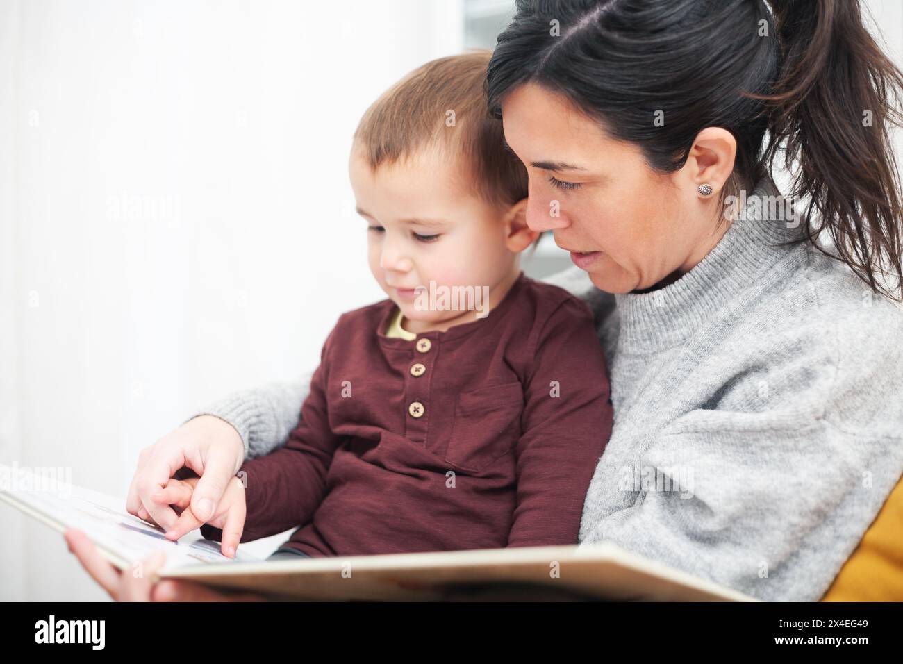 A woman and a child are sitting together and reading a book. Concept of ...