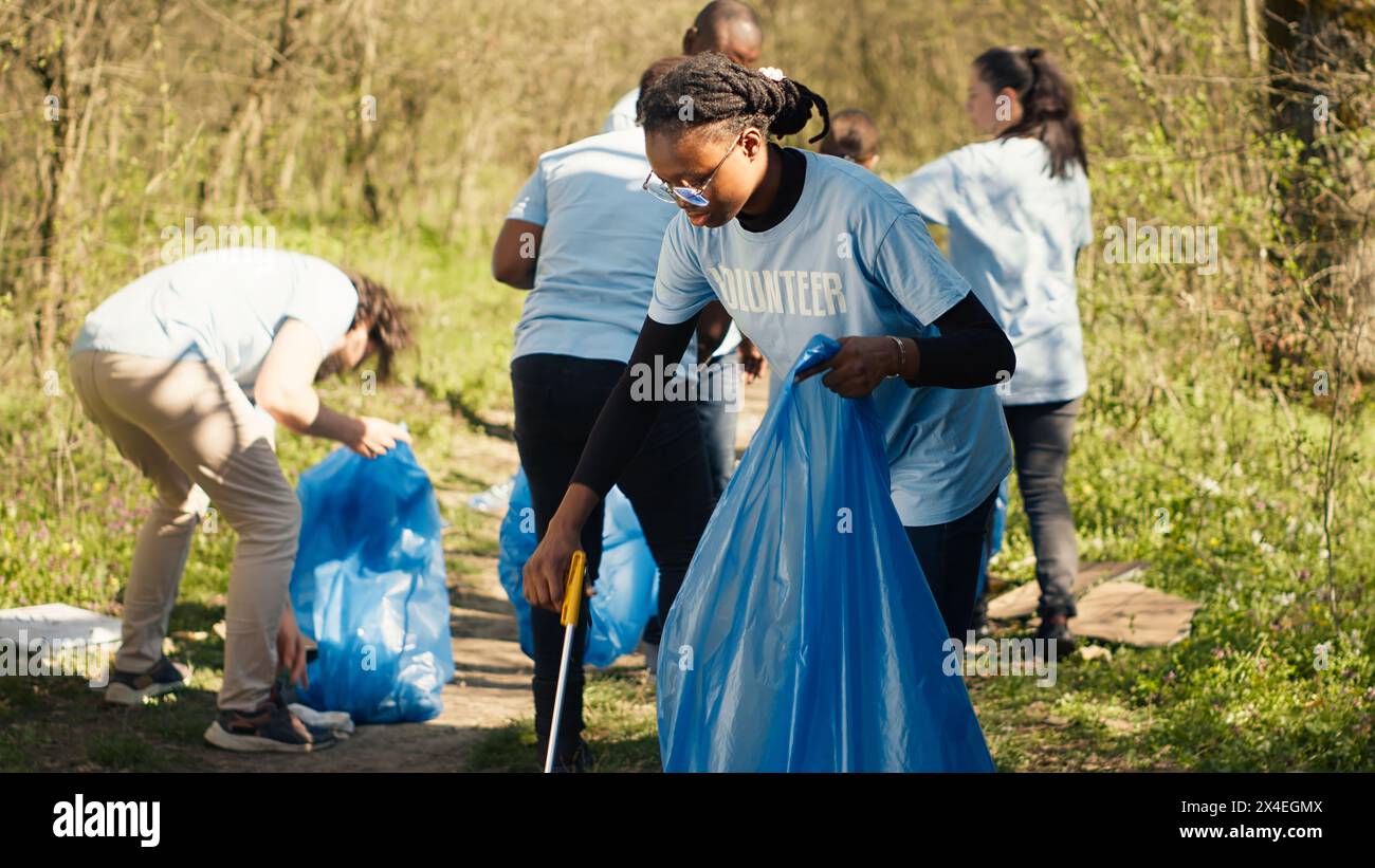 African american girl picking up trash with a long claw and garbage ...