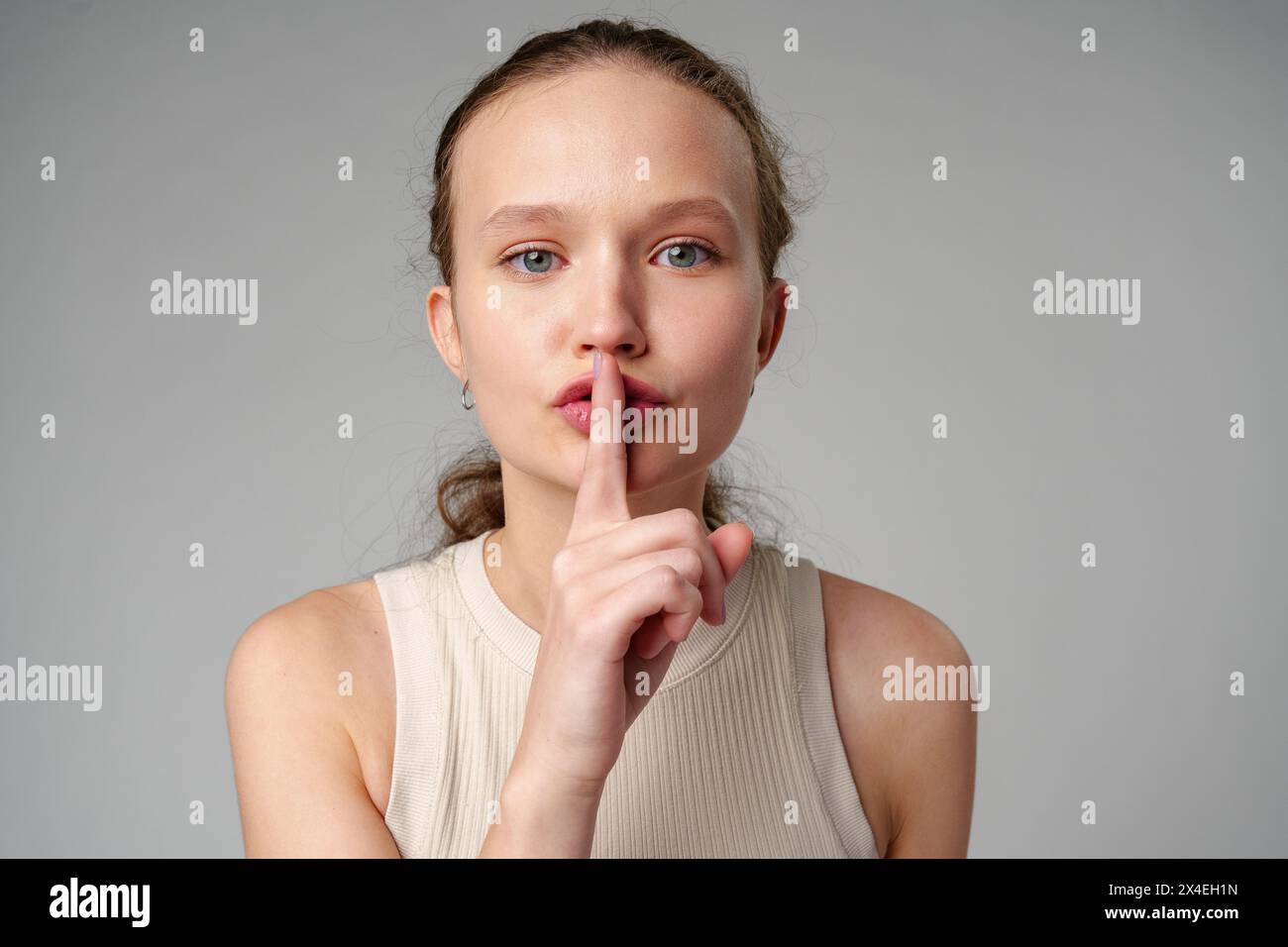 Young Woman Making a Hush Gesture on gray background in studio Stock ...