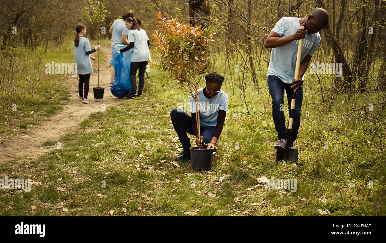 African american volunteers team digging holes and planting trees in a ...