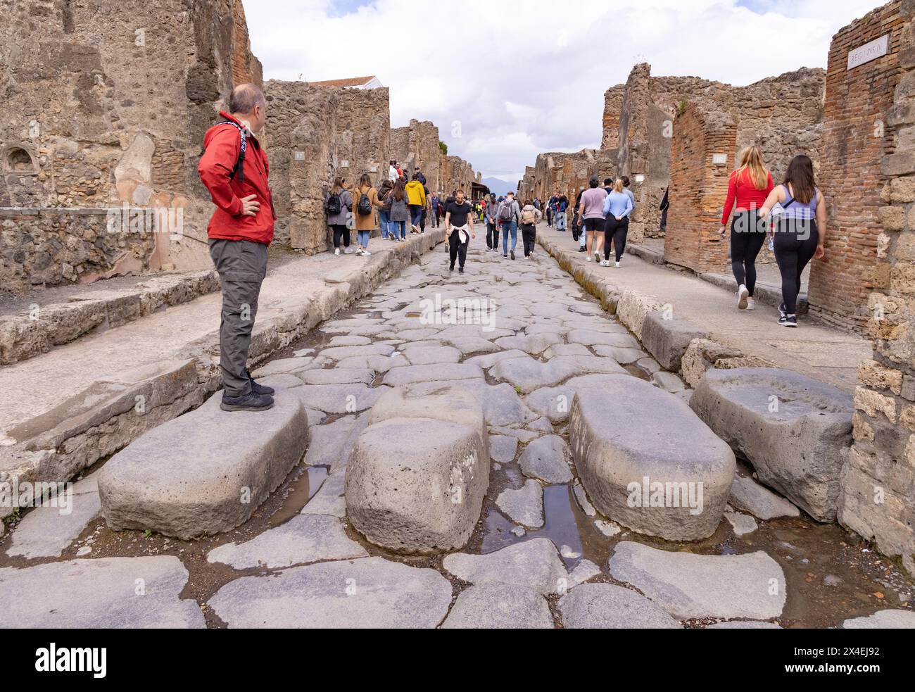 A tourist standing on the pedestrian crossing on a roman road; the ...