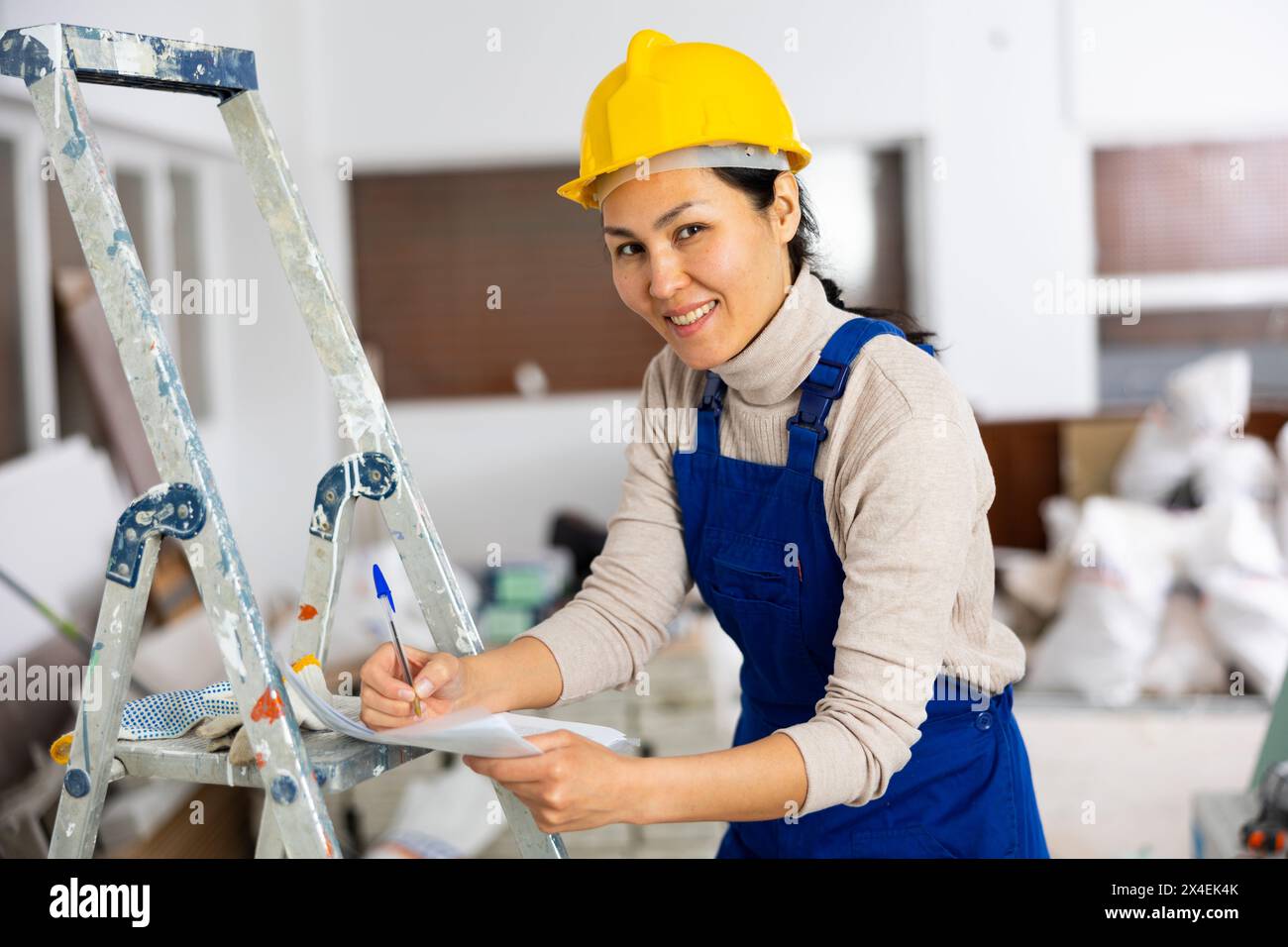 Positive woman builder filling project documentation Stock Photo - Alamy