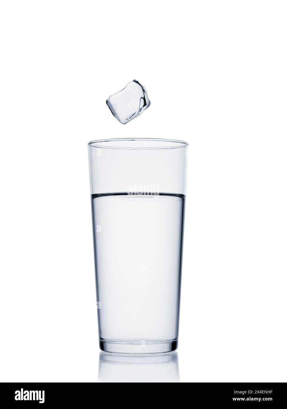 Ice cube dropping into a glass of water isolated on white background ...